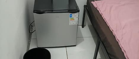 Quarto pequeno com cama, aquecedor e lixeira.