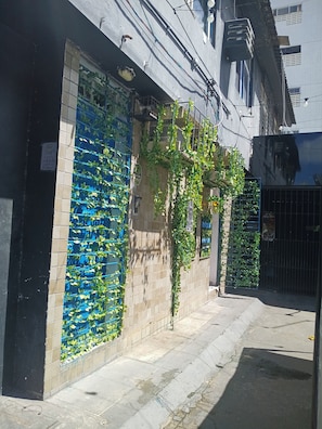 Um edifício com fachada em azulejos, portão de metal e parede coberta de trepadeiras.