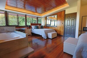Um quarto espaçoso com uma cama grande, uma área de estar e um banheiro com banheira.