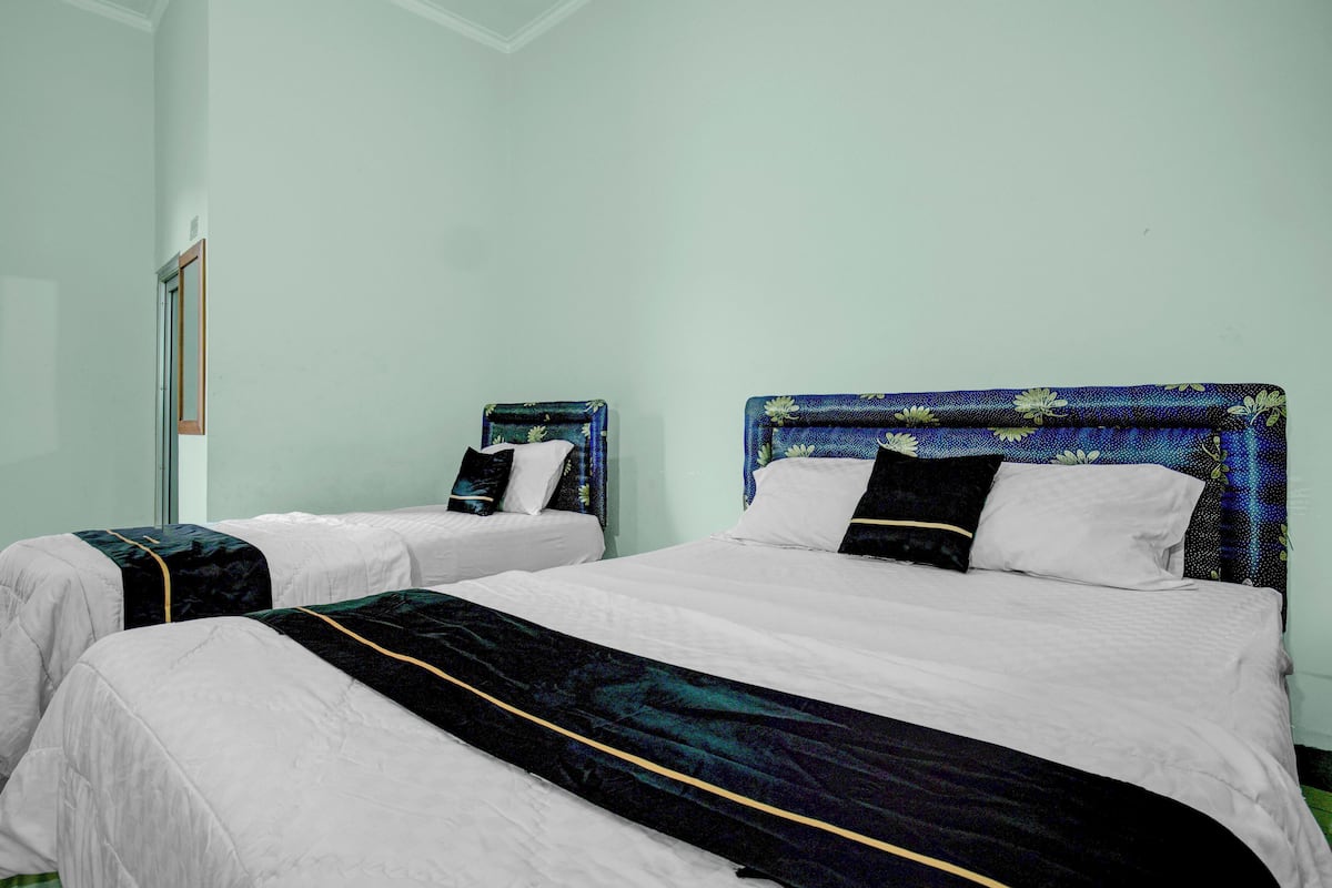 Duas camas de solteiro com cabeceiras, roupa de cama branca e um cobertor azul escuro.