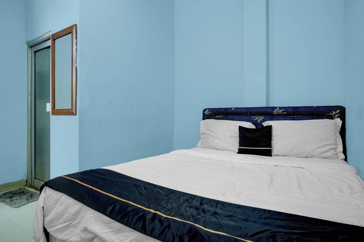 Um quarto com uma cama, uma porta e um espelho fixado na parede.