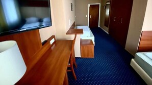 Quarto de hotel com televisão, móveis de madeira, cama e tapete azul.