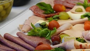 Tábua de frios com diversos queijos, carnes e legumes.