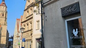 Um hotel com uma placa que diz 'Hotel Ratskeller' e um logotipo de galo.