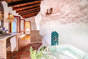 Um interior rústico com parede de pedra, teto de madeira, área de cozinha e banheira.