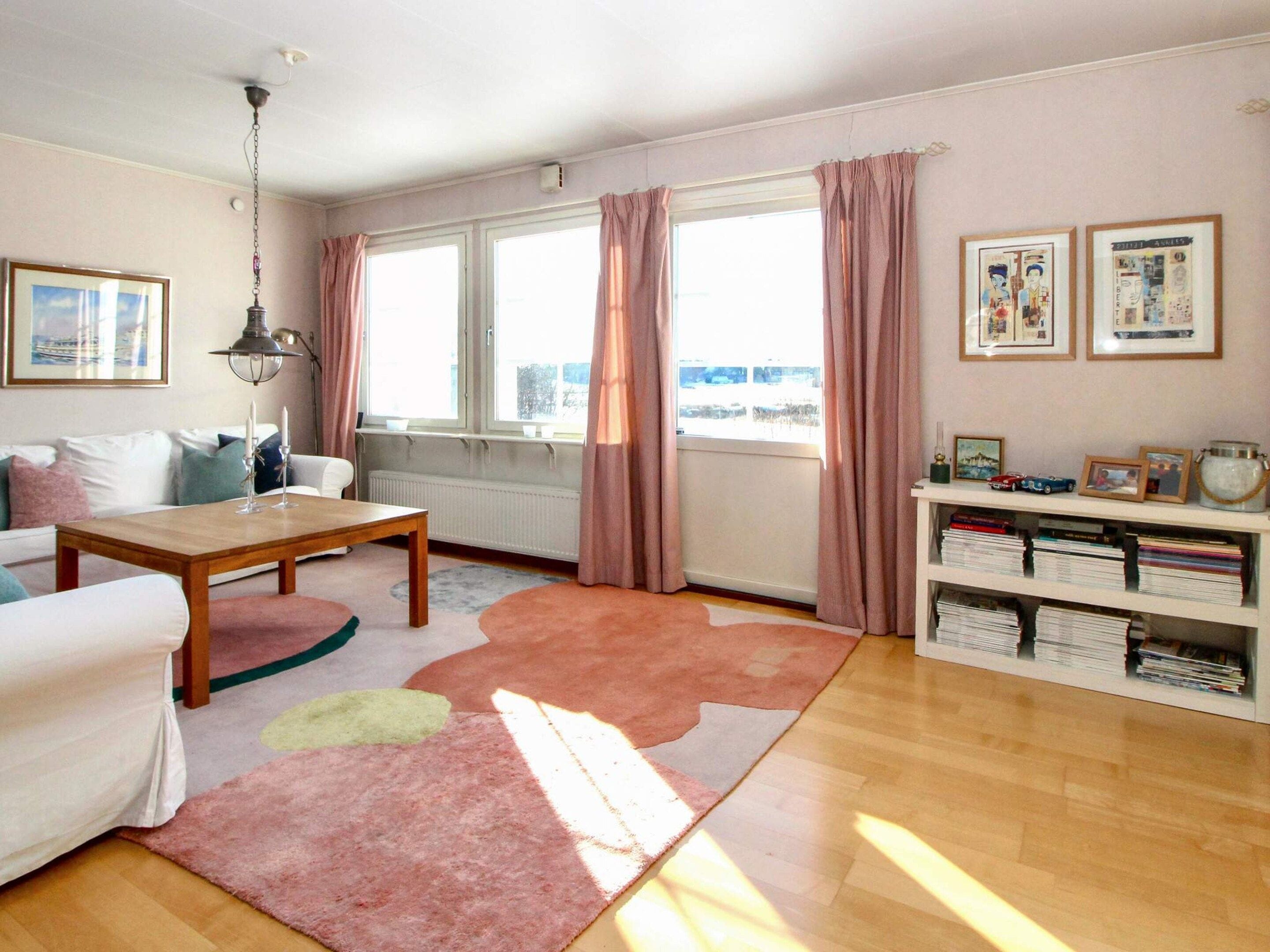 Uma sala de estar com sofá, mesa de centro, estante e janela com cortinas.