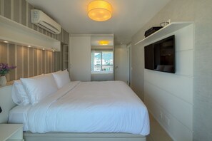 Quarto de hotel moderno com uma cama grande, ar condicionado, televisão de tela plana e varanda com vista.
