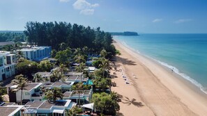 Um imóvel à beira-mar com várias acomodações estilo bangalô, uma praia de areia e vista desobstruída do oceano.