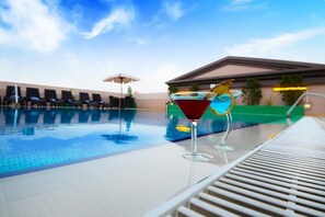 Piscina com espreguiçadeiras e um edifício ao fundo.