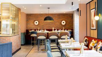 Um restaurante com paredes de tijolo, iluminação moderna e uma variedade de assentos, incluindo mesas e cabines.