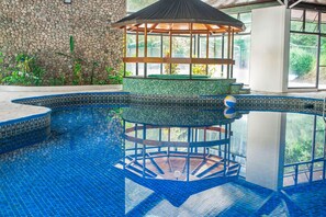Piscina com deck circular, gazebo e muro de pedra.