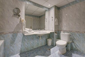 Casa de banho com lavatório, espelho, sanita e um cesto de lixo.