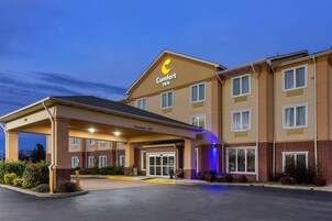 Um hotel Comfort Inn com entrada coberta, várias janelas e céu claro.