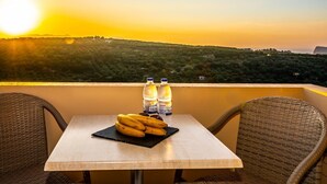 Varanda com mesa, cadeiras de vime, bananas e garrafas de água.