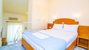 Quarto de hotel com uma cama grande, mesas de cabeceira, painel de madeira na cabeceira e janela com cortinas.