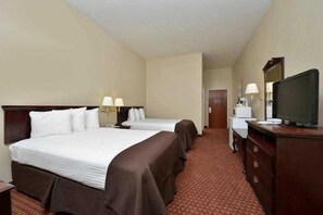 Quarto de hotel com duas camas, uma cômoda, uma televisão e uma porta que dá para outro espaço.