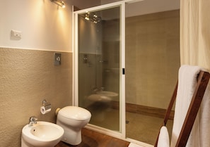 Casa de banho com sanita, bidé e cabine de duche com vidro.