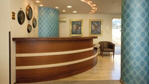 Uma receção com design curvo, uma cadeira e obras de arte emolduradas nas paredes.