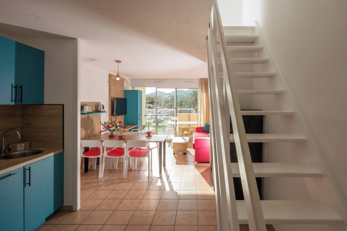 Uma cozinha moderna com área de jantar, escada e vista para o exterior.