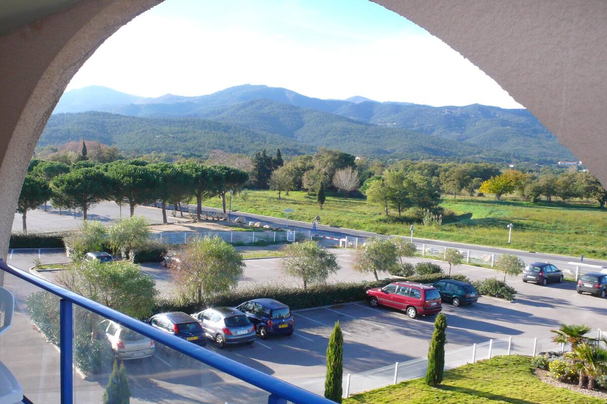 Uma varanda com vista para um estacionamento e montanhas ao longe.