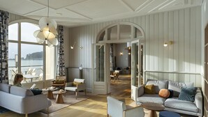 Uma sala ampla com uma grande janela, um sofá, uma mesa de centro e um espaço de jantar com cadeiras.