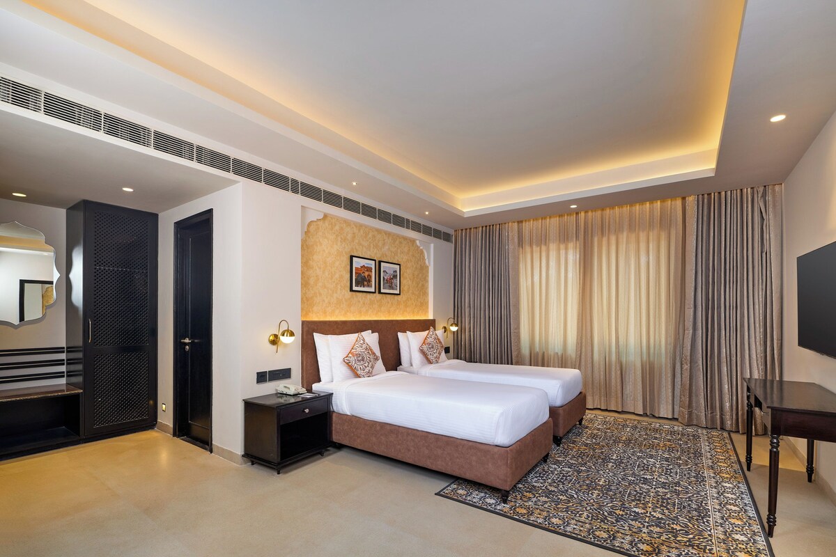 Quarto de hotel moderno com uma cama grande, televisão de tela plana, escrivaninha e tapete estampado.