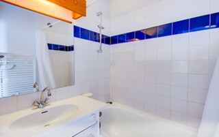 Casa de banho com lavatório branco, espelho e banheira.