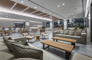 Uma área de estar moderna com sofás, cadeiras e mesas, apresentando um design contemporâneo e muitos assentos.