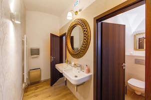 Casa de banho com duas pias, um espelho e uma sanita.