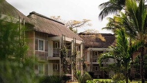 Um hotel com edifícios de telhado de palha, um jardim bem cuidado e céu limpo.