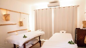 Quarto com duas camas, um banco de madeira, uma mesinha e ar-condicionado fixado na parede.