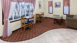 Um quarto com uma mesa de jantar, cadeiras, um sofá, um radiador e uma janela com cortinas.