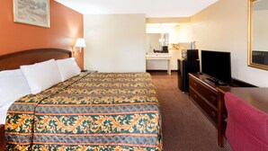 Quarto de hotel com uma cama, televisão, escrivaninha e espelho.