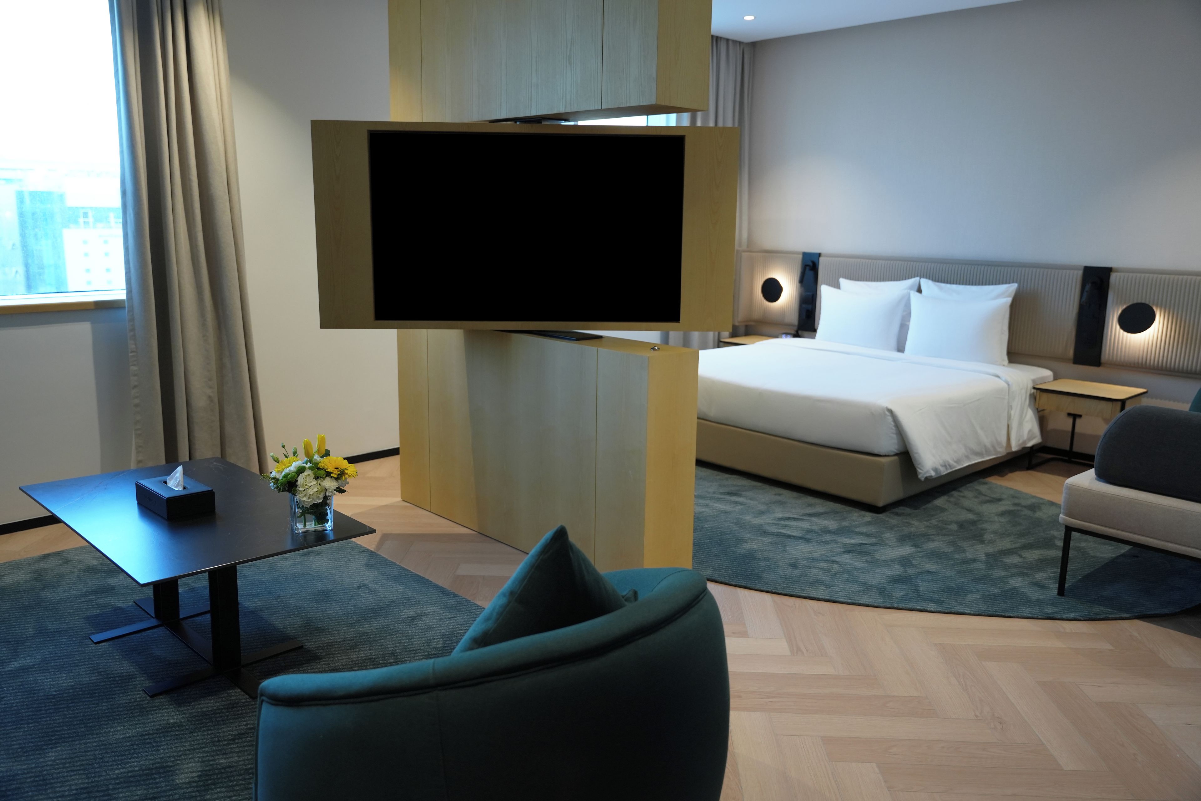 Quarto de hotel moderno com cama, televisão, escrivaninha e cadeira.