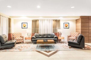 Uma sala de estar com sofá, duas poltronas, uma mesa de centro e um tapete.
