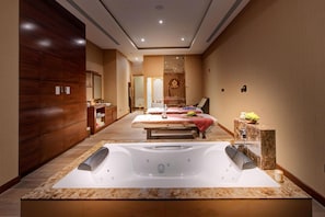 Um quarto de spa com uma banheira grande, uma mesa de massagem e um painel de parede de madeira.