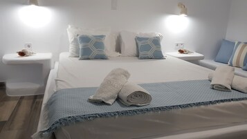 Quarto de hotel com cama, duas mesas de cabeceira e um criado-mudo.