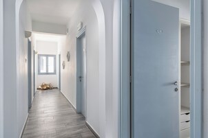 Um corredor com piso de madeira, paredes brancas e uma porta azul.