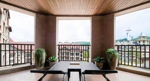 Varanda com teto de madeira, duas plantas em vasos, uma mesa e cadeiras.