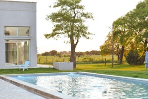 Uma casa moderna com piscina, gramado e uma árvore.