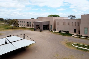 Um edifício com teto plano, entrada coberta e calçada pavimentada.