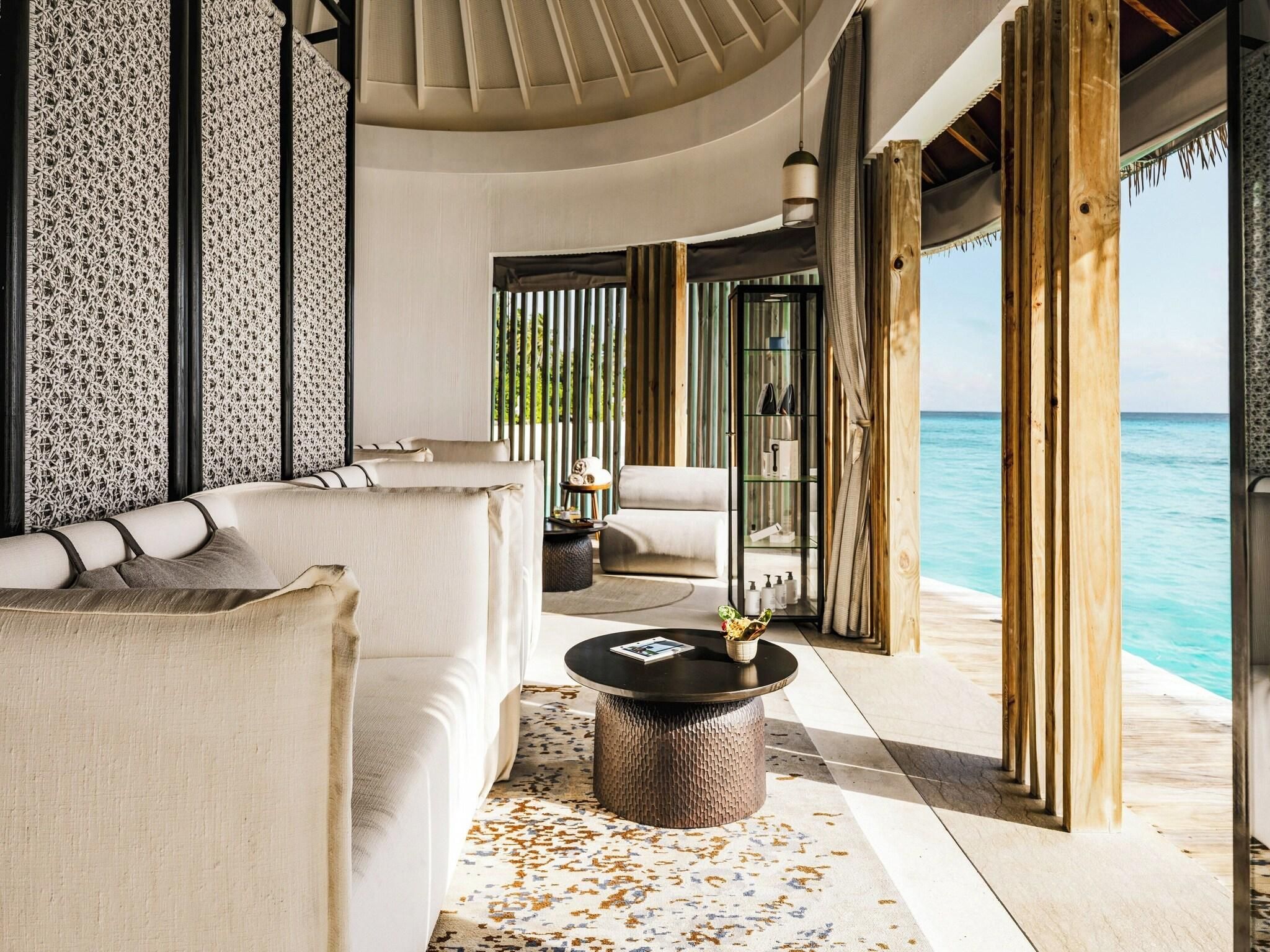 Um quarto luxuoso com teto curvo, um sofá, uma mesa de centro e vista para o oceano.