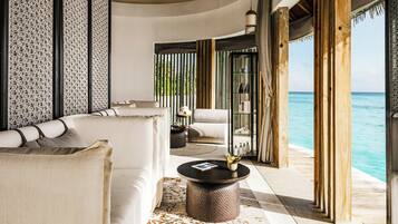 Um quarto luxuoso com teto curvo, um sofá, uma mesa de centro e vista para o oceano.