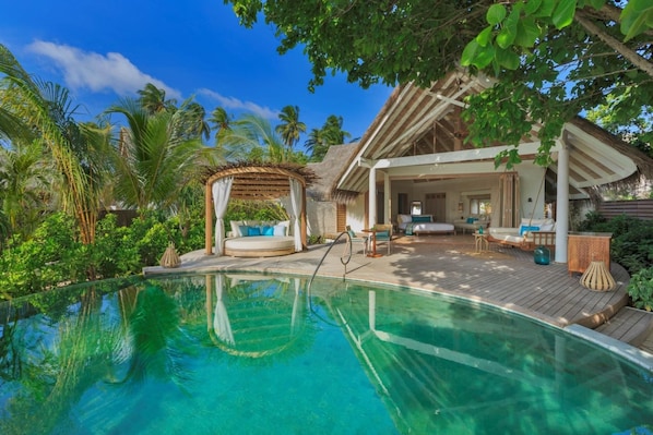 Um resort com piscina, cabana e área de estar coberta com vista para a piscina.