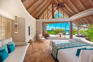 Um quarto espaçoso com uma cama grande, um sofá, uma mesa de jantar e vista para o mar.