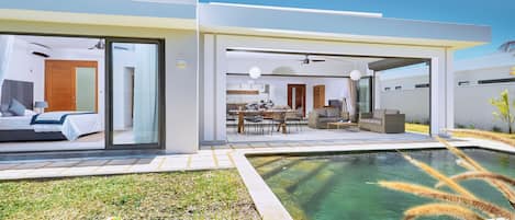 Uma casa moderna com piscina, área de refeições e um quarto com porta de vidro deslizante.