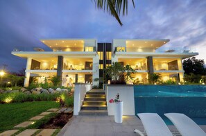 Uma casa moderna de dois andares com piscina, iluminação externa e um jardim bem cuidado.