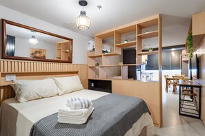 Quarto de hotel moderno com uma cama grande, área de trabalho e espaço para refeições.