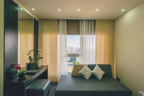Quarto de hotel moderno com uma cama, mesa de cabeceira, espelho e janela com vista para a cidade.