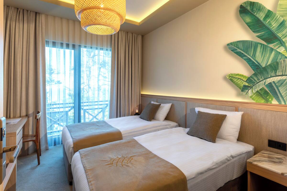 Quarto de hotel com duas camas, uma escrivaninha e uma cadeira.